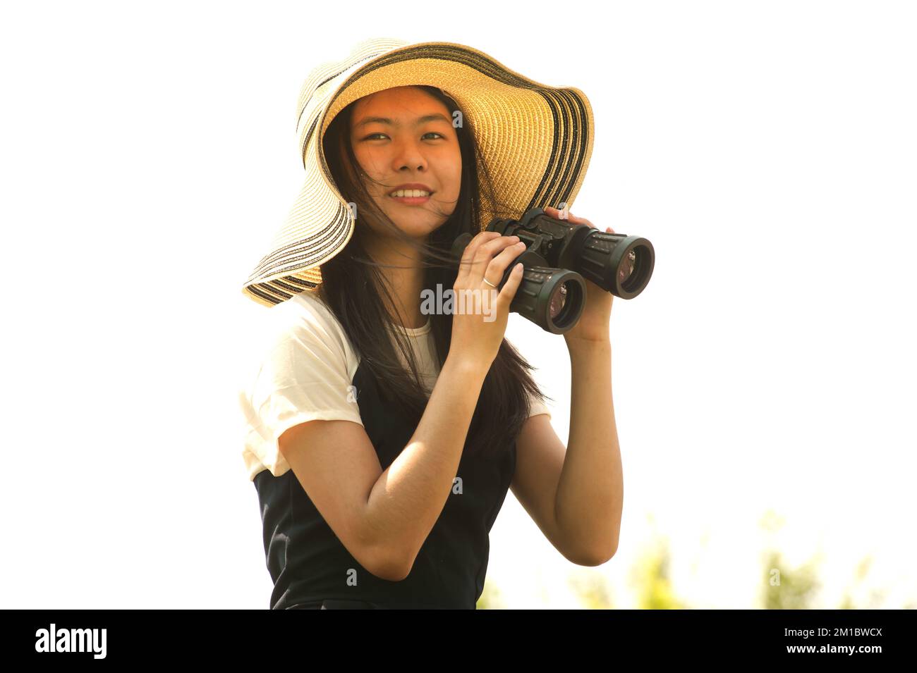 Pretty Asian young woman sit on mound seeking binoculars Stock Photo ...