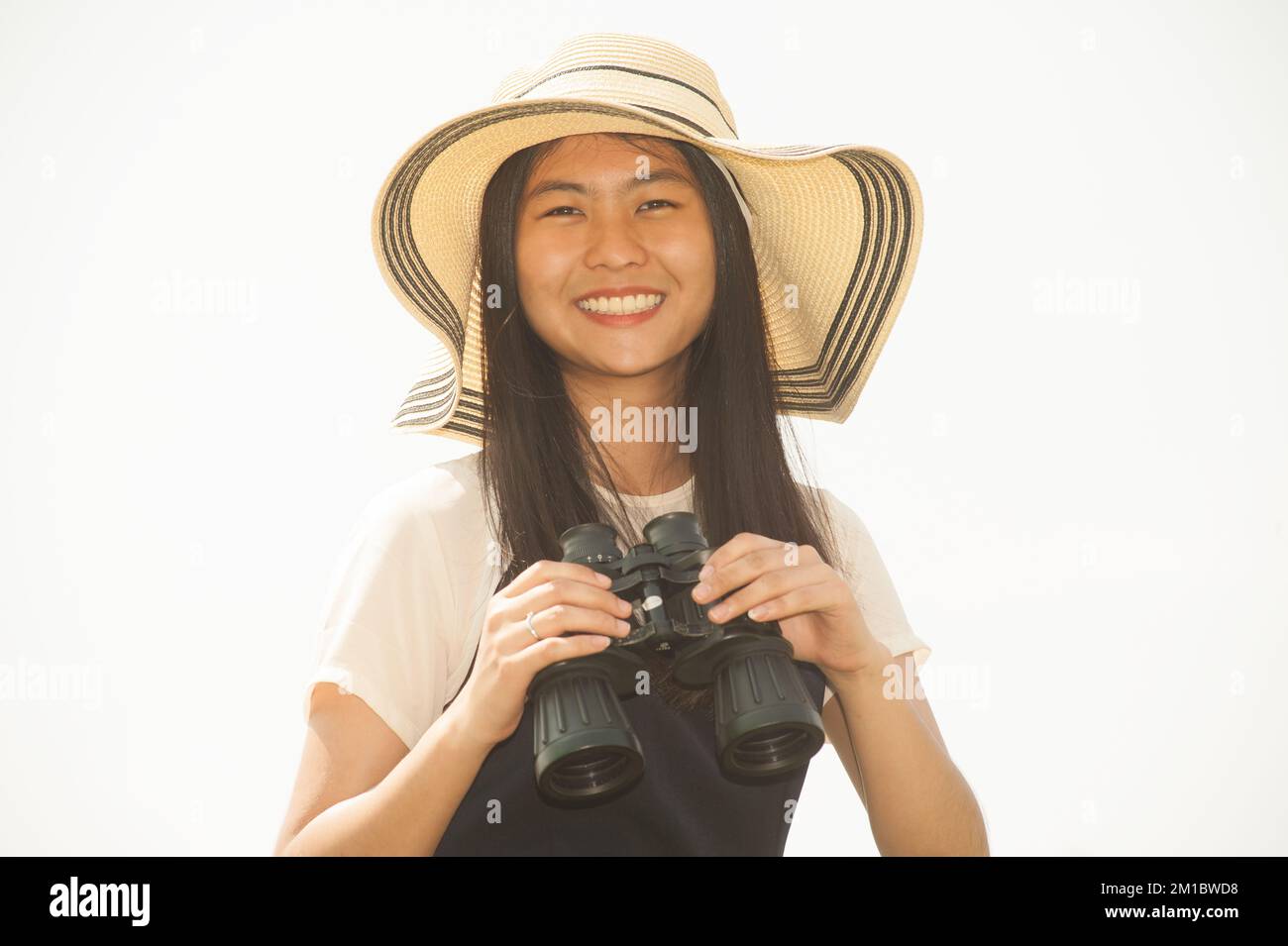 Pretty Asian young woman sit on mound seeking binoculars Stock Photo ...