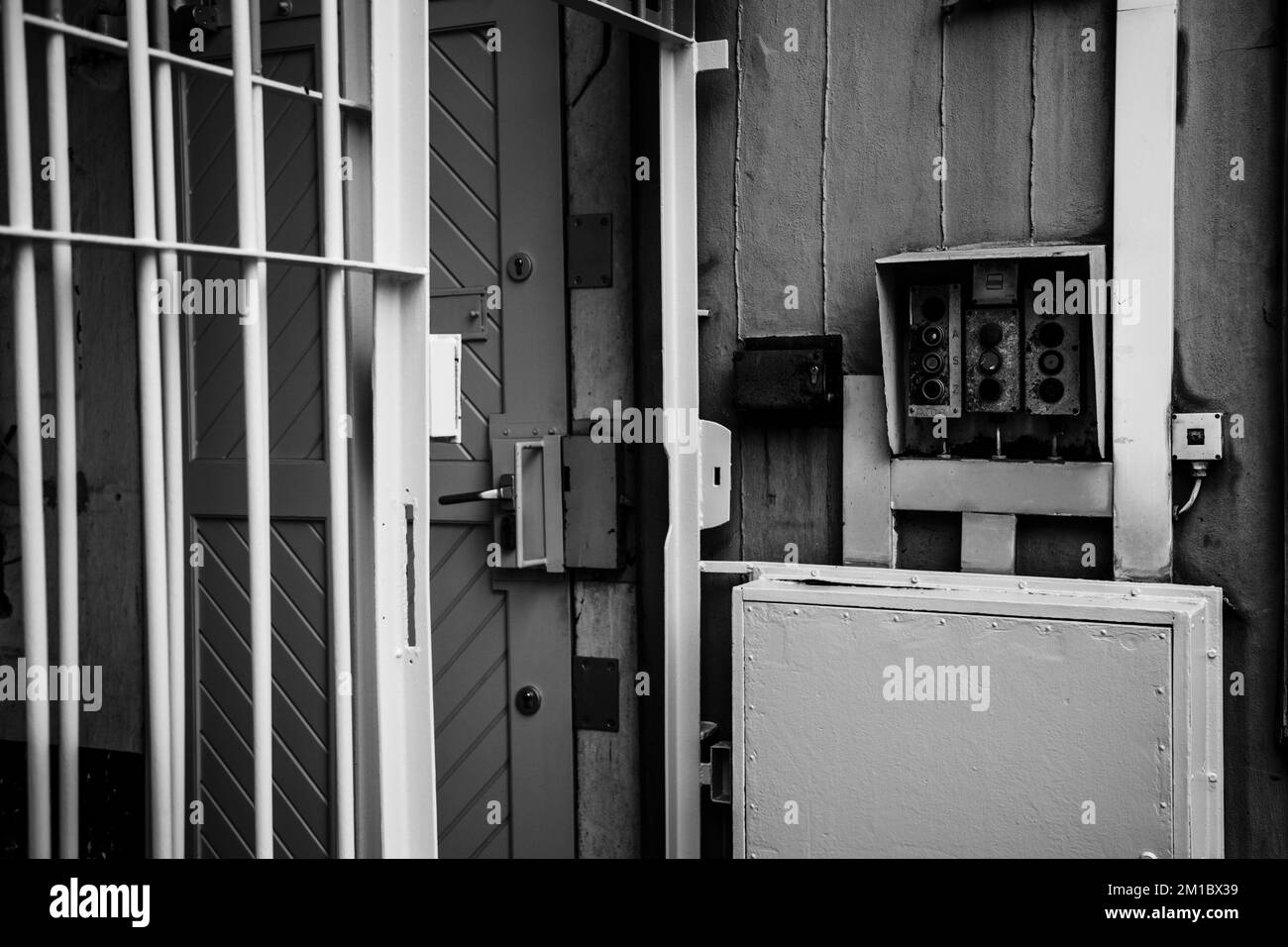 A grayscale shot of an electricity box next to a door of a building ...