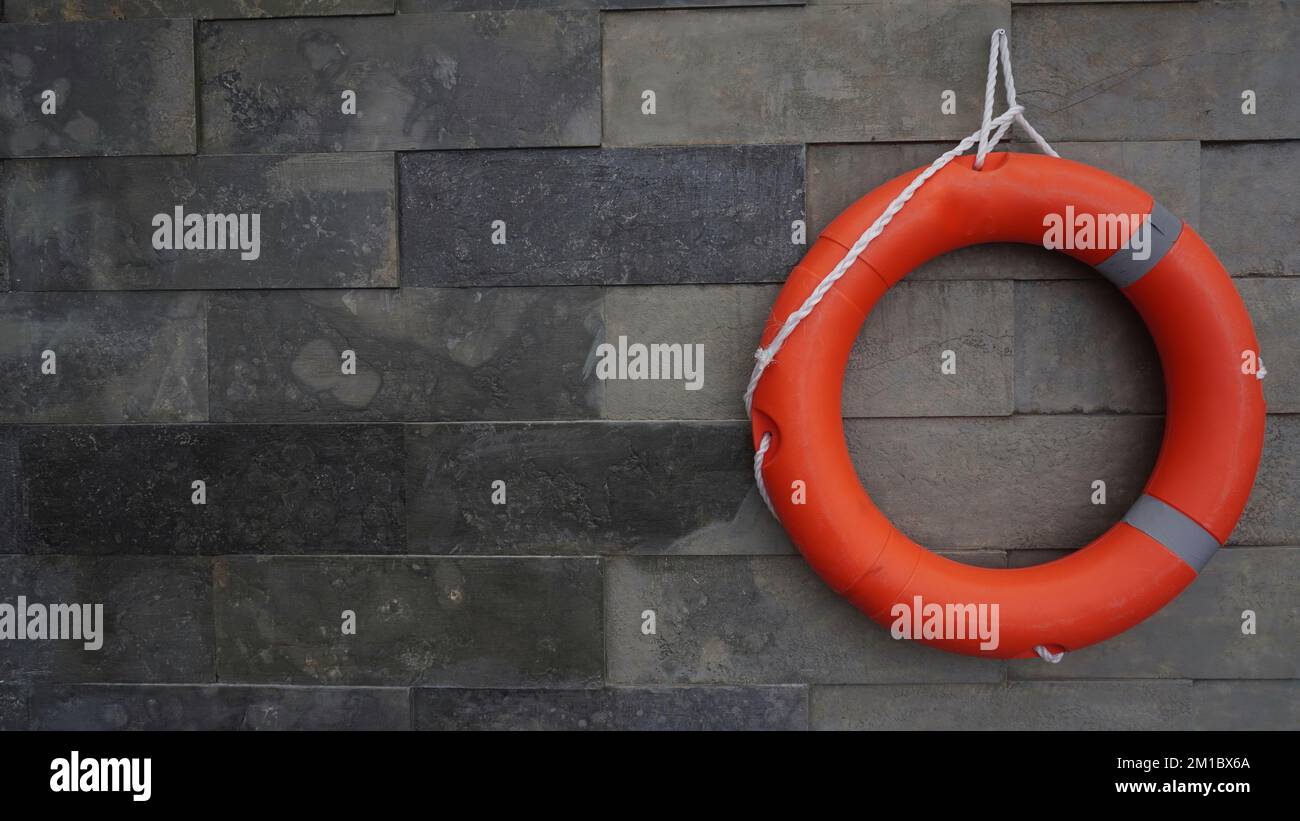 orange lifebuoy hanging in the stone wall of swimming pool. safety for ...