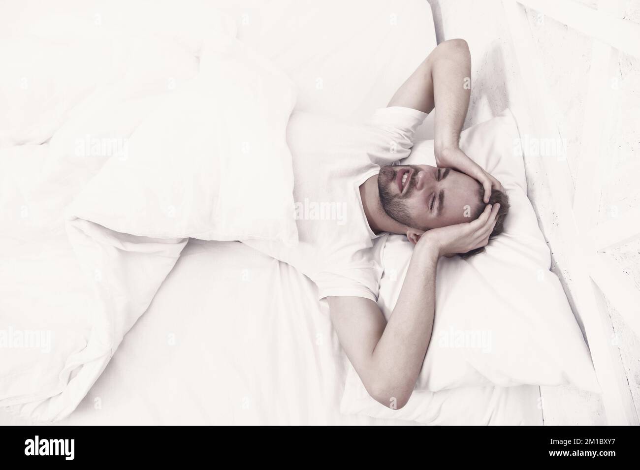 Sleep problems can lead to headaches in morning. Handsome man relaxing ...
