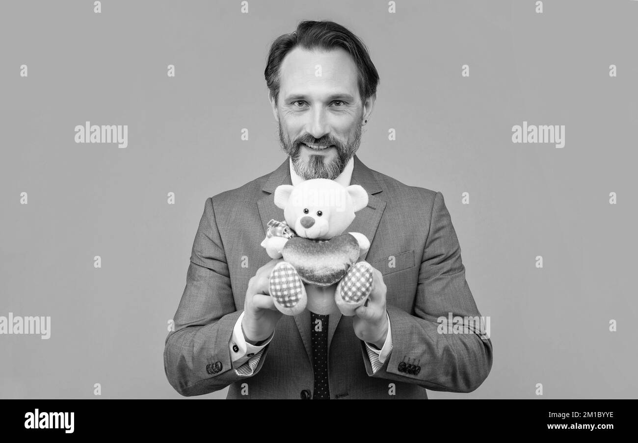 happy senior man in suit hold toy bear on grey background, birthday ...