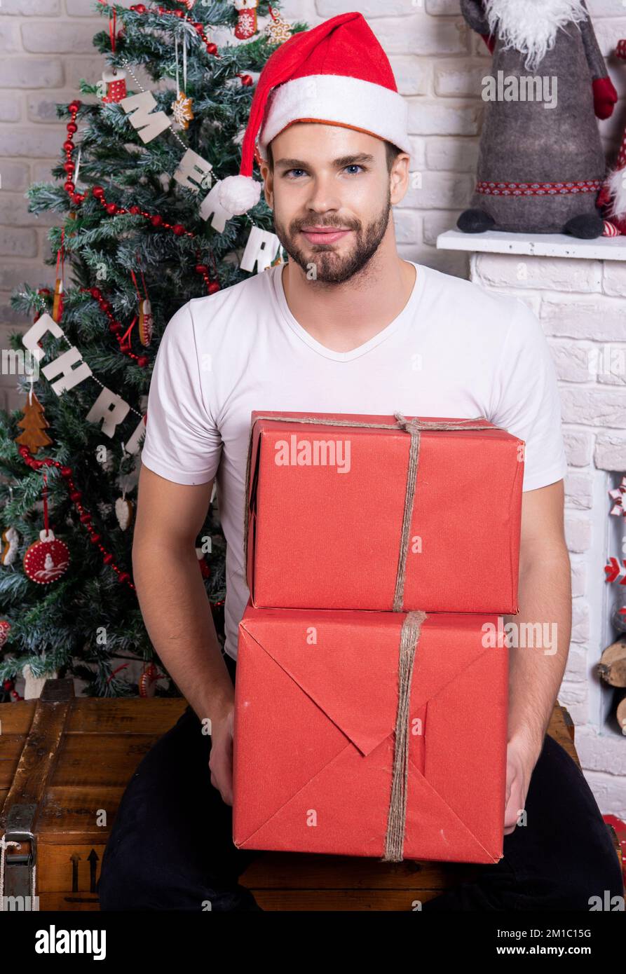 smiling man with red christmas present in studio. santa man at ...