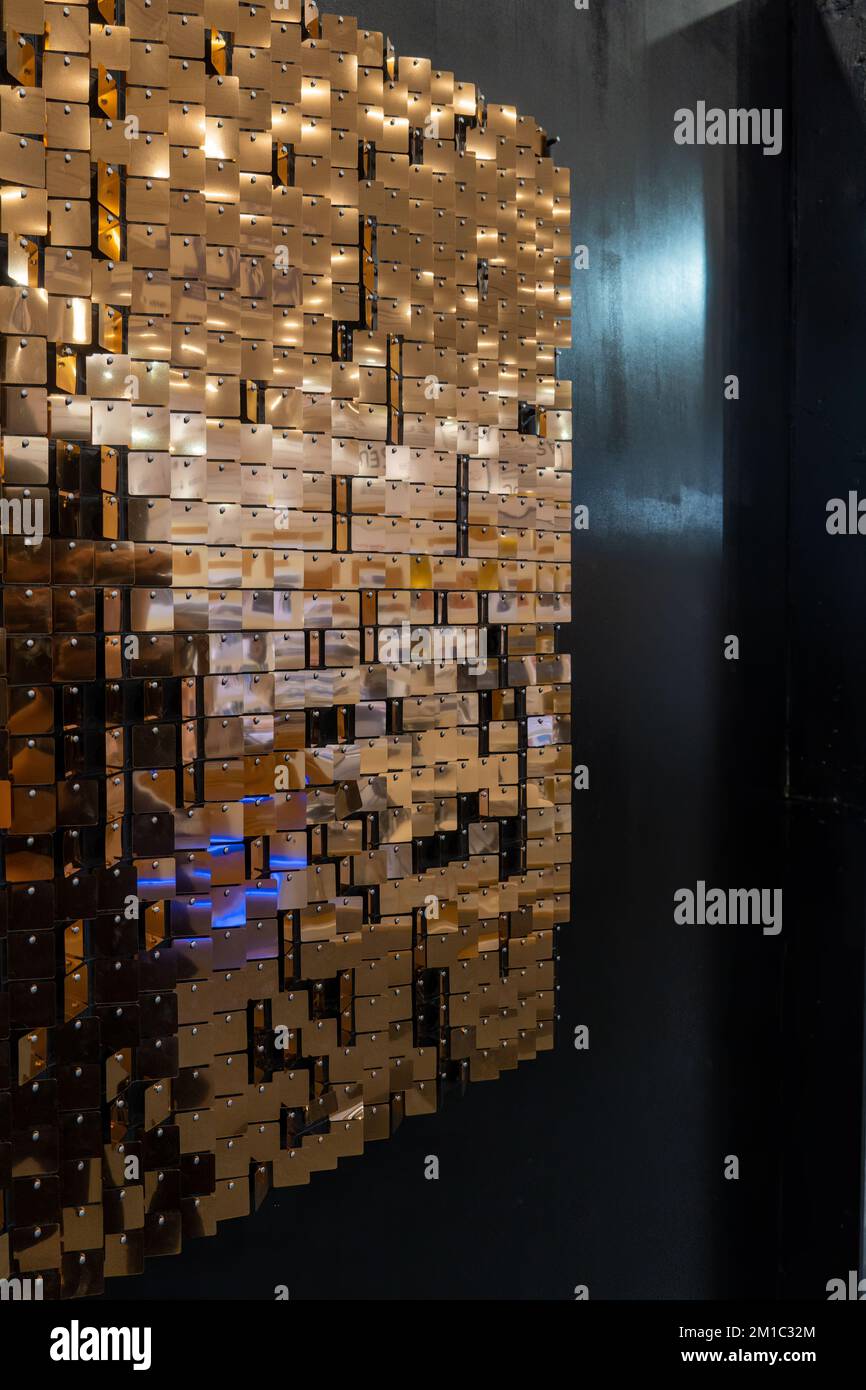 reflection of small copper pieces on a black wall, reflecting people ...