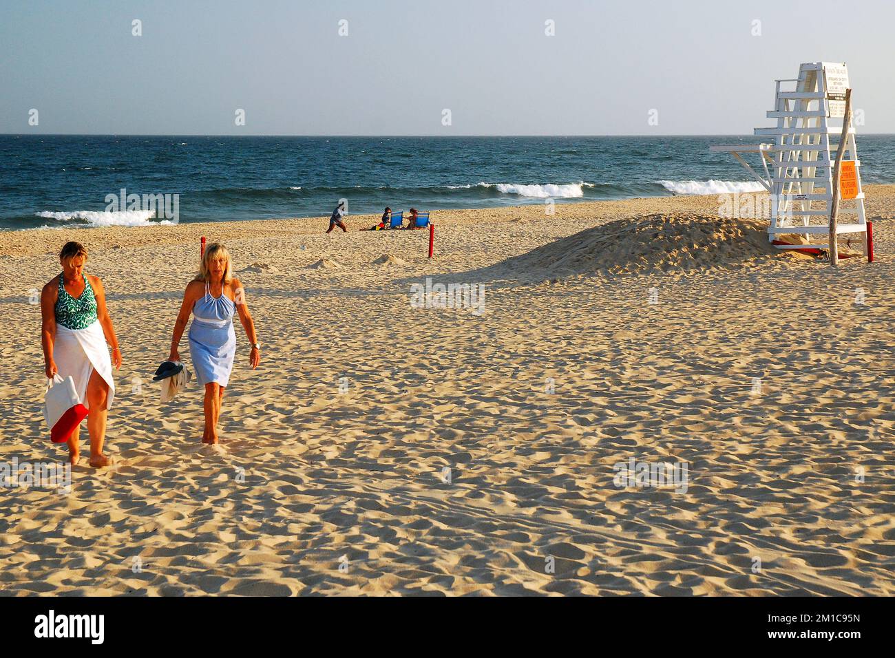Two Adult women friends exit the beach on a late summer's afternoon in ...