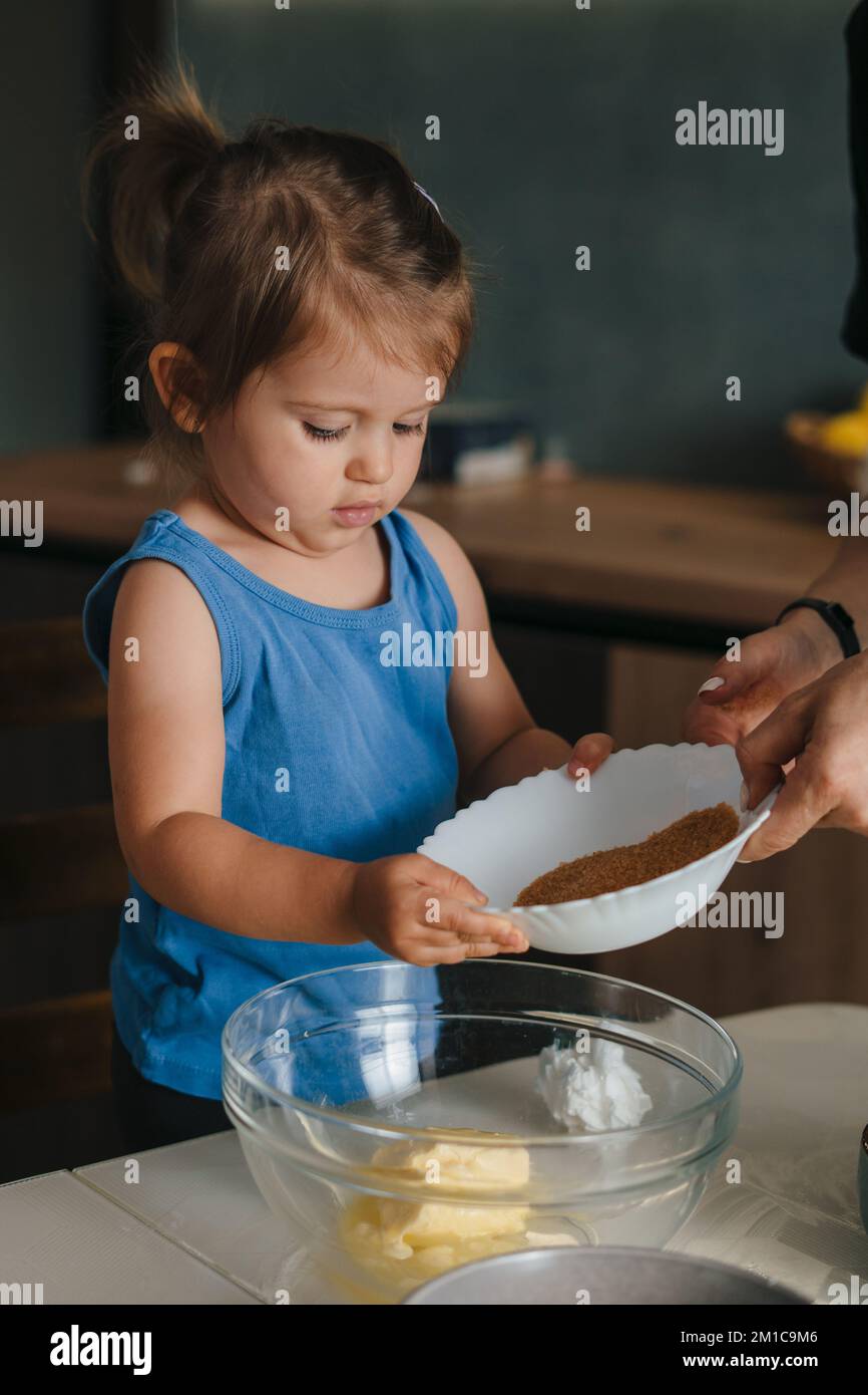 Mother making a cake with the help of children to have fun. Mom and ...
