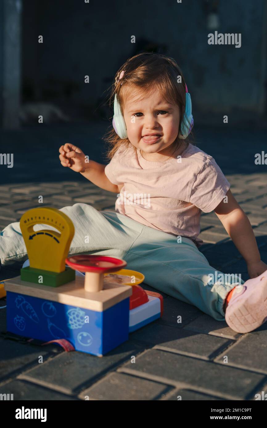 Baby girl standing outside on the terrace playing with a colorful and ...