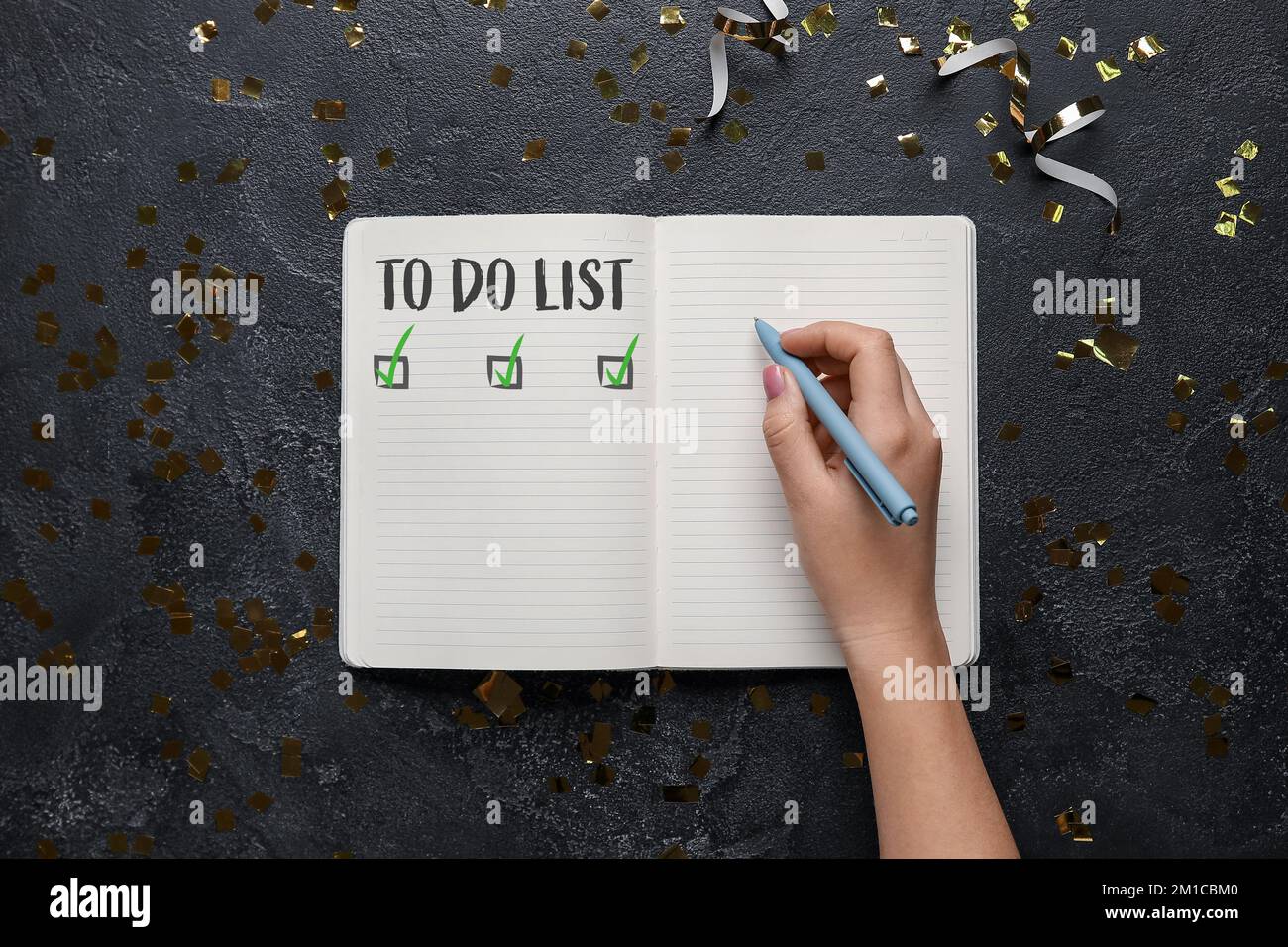 Woman making to-do list for year 2023 on dark background, top view ...