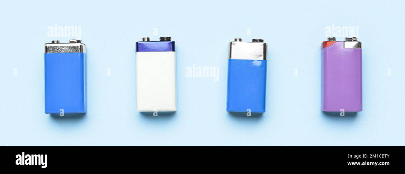 Different alkaline batteries on light blue background Stock Photo - Alamy