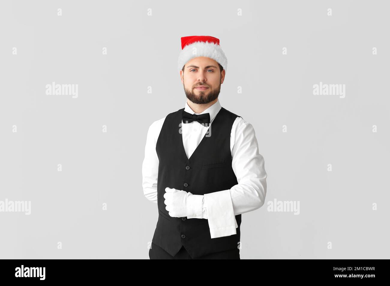 Handsome male waiter in Santa hat on grey background Stock Photo - Alamy