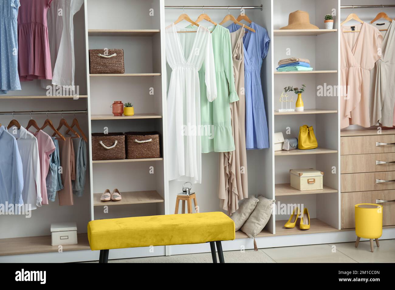 Interior of walk-in closet with trendy clothes and yellow bench Stock ...