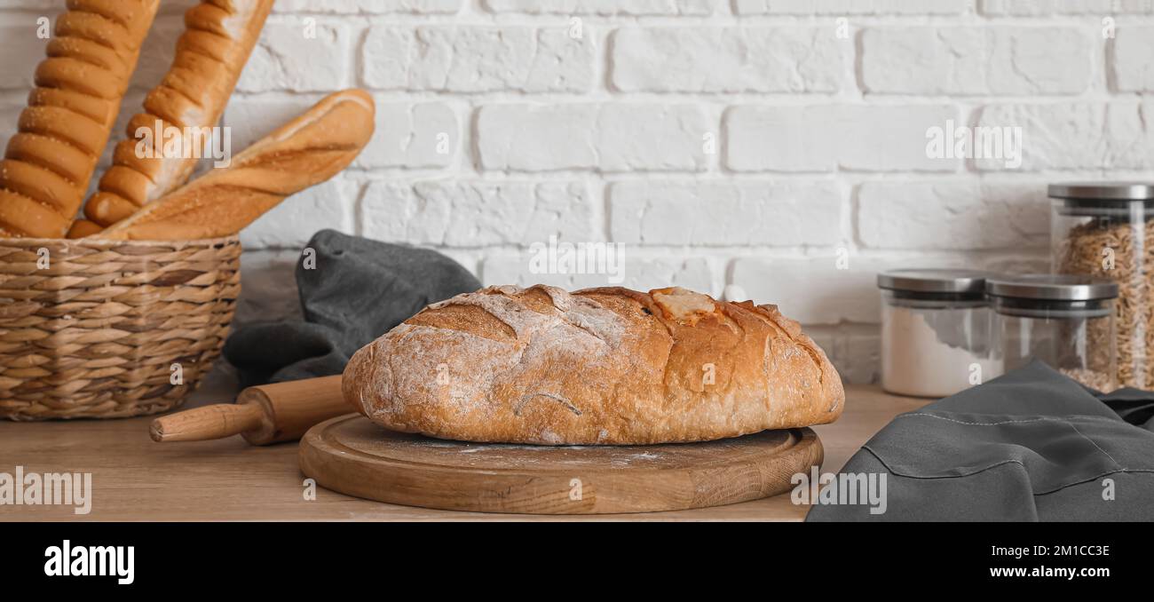 Counter with fresh bread near white brick wall in kitchen Stock Photo ...