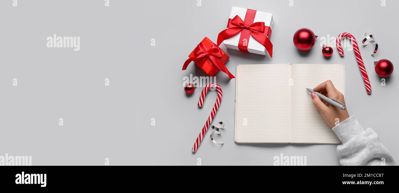 Female hand writing in blank notebook, Christmas gifts and balls on ...