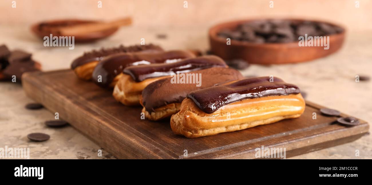 Wooden board with sweet eclairs on beige background Stock Photo - Alamy