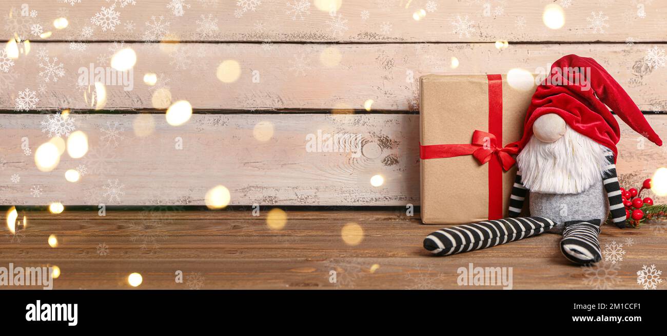Christmas gnome with gift on wooden background with space for text ...