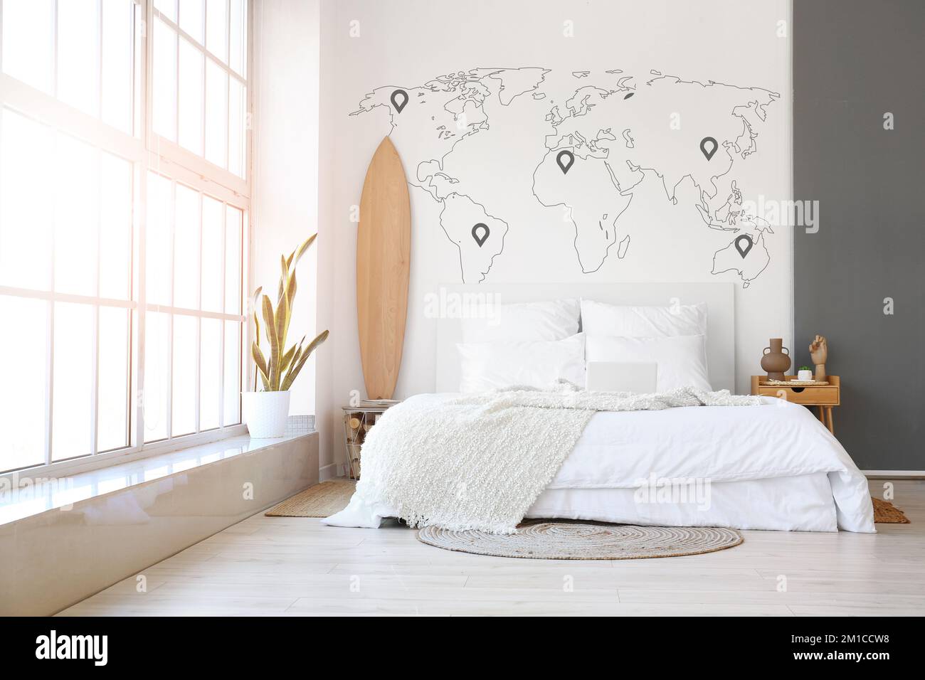 Interior of light bedroom with surfboard and printed world map on wall ...