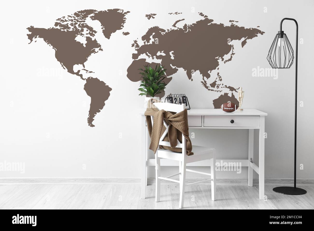 Table with chair, lamp and printed world map on wall in office Stock ...
