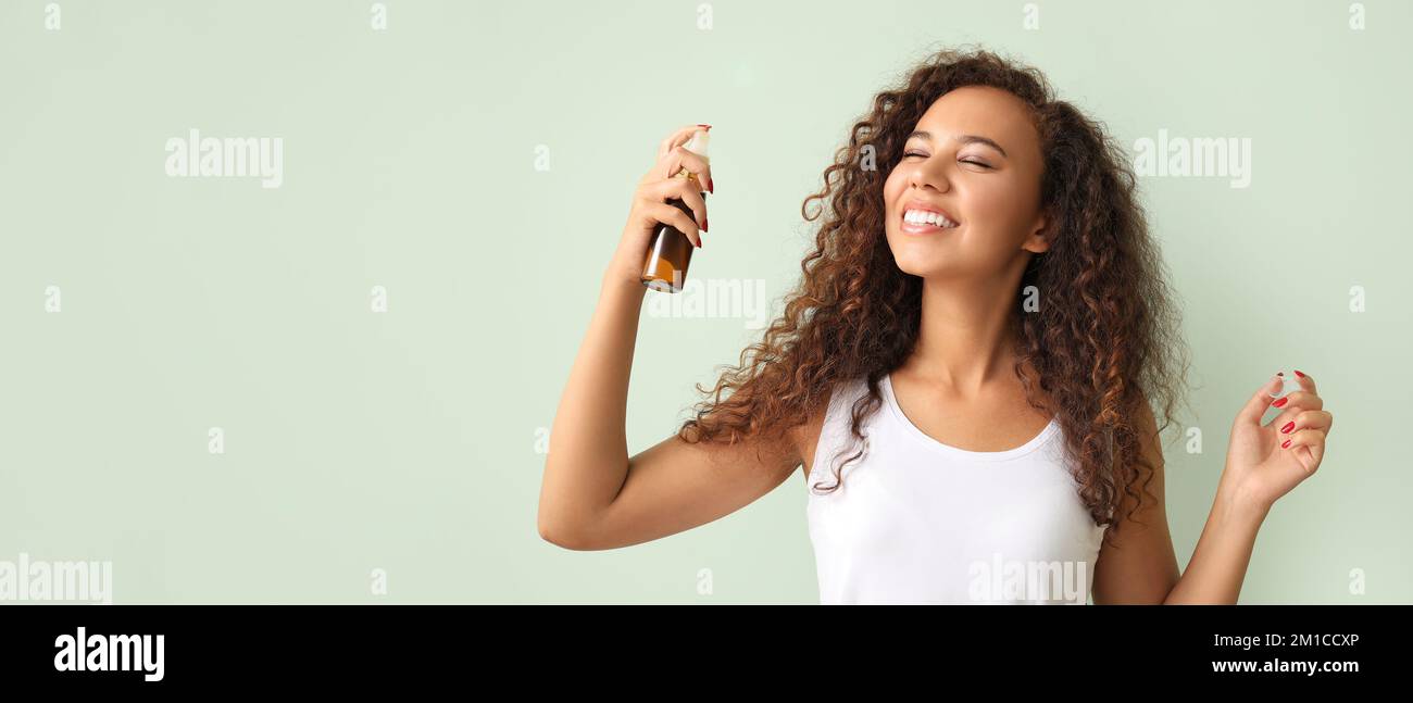 Beautiful young African-American woman with cosmetic oil on color ...