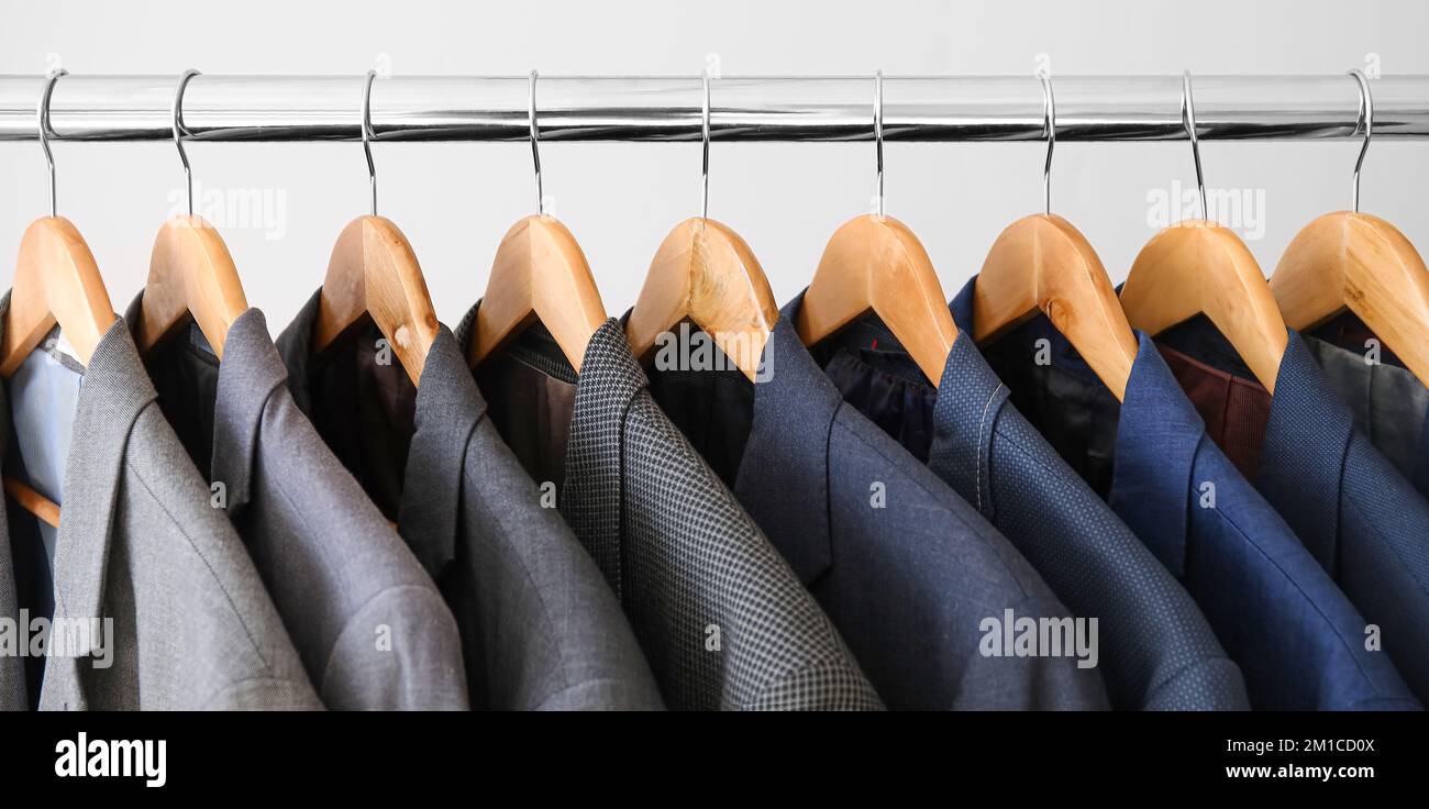 Rack with different stylish male suits on light background Stock Photo ...