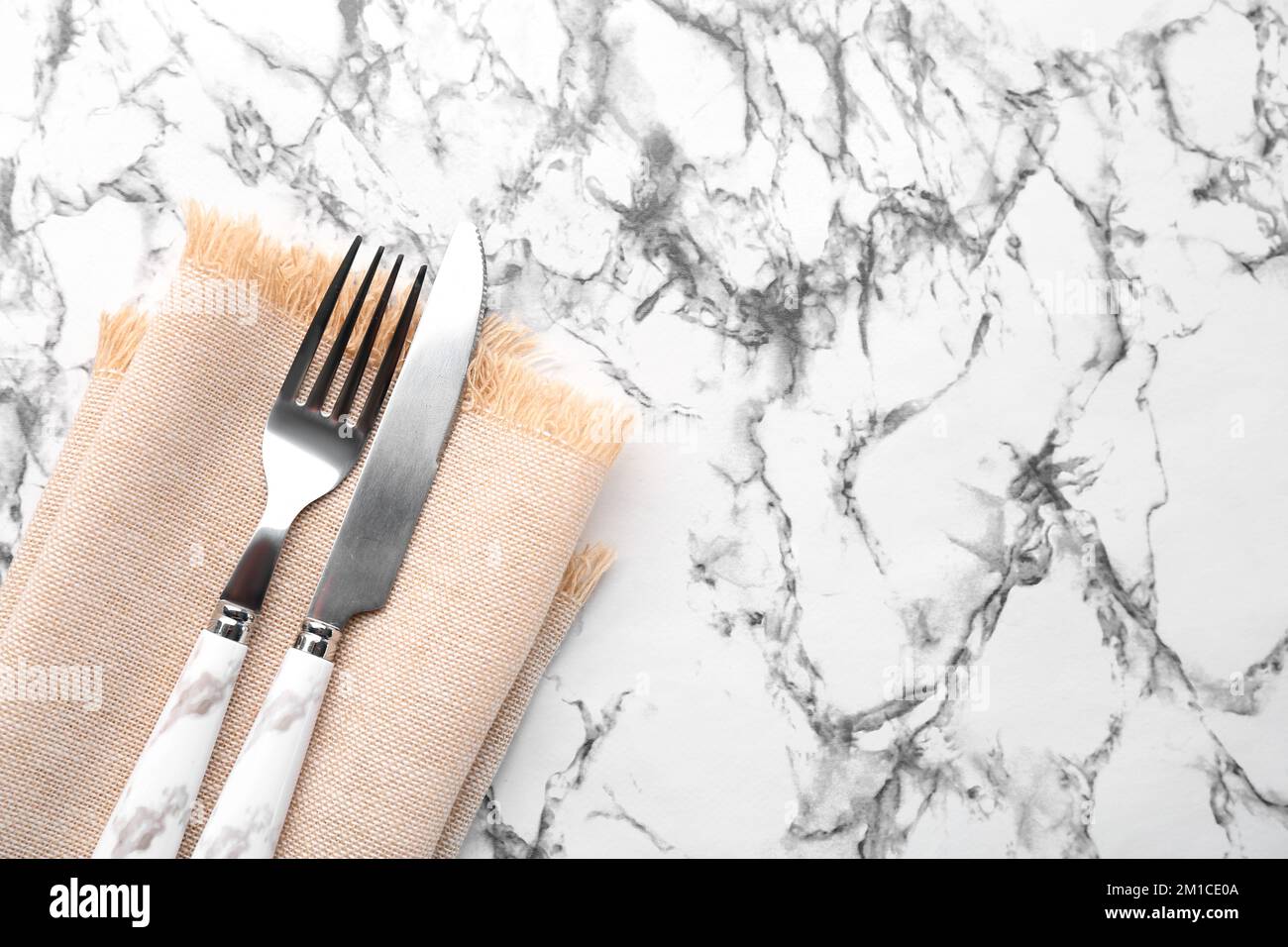 Silver cutlery with napkin on white marble background, closeup Stock ...