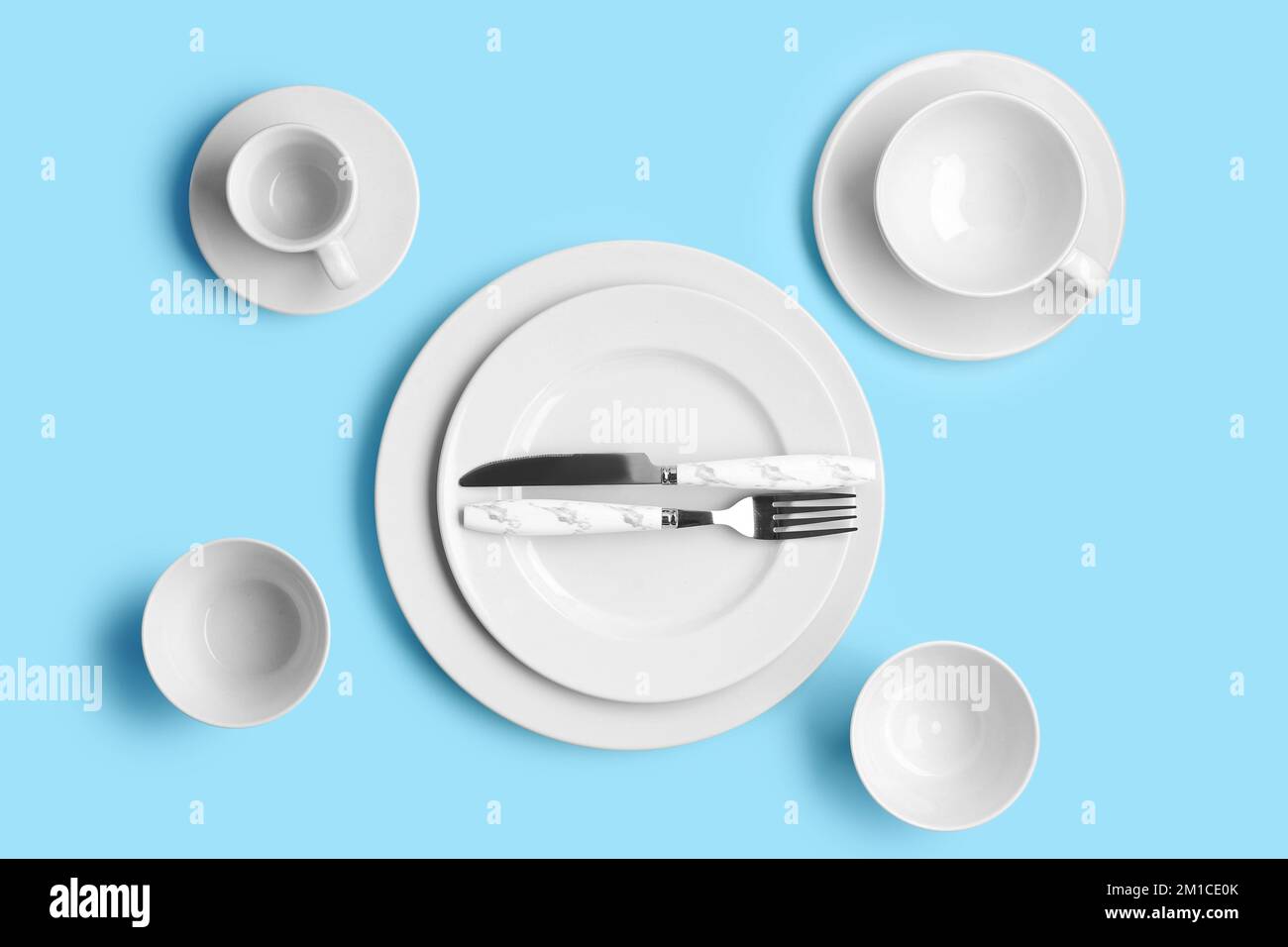 White table setting on blue background Stock Photo - Alamy