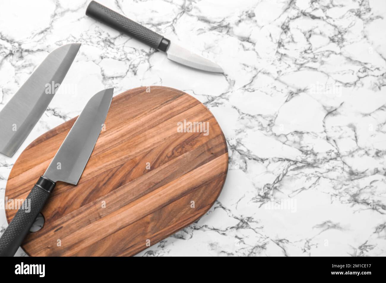 Wooden cutting board with knives on white marble background Stock Photo ...