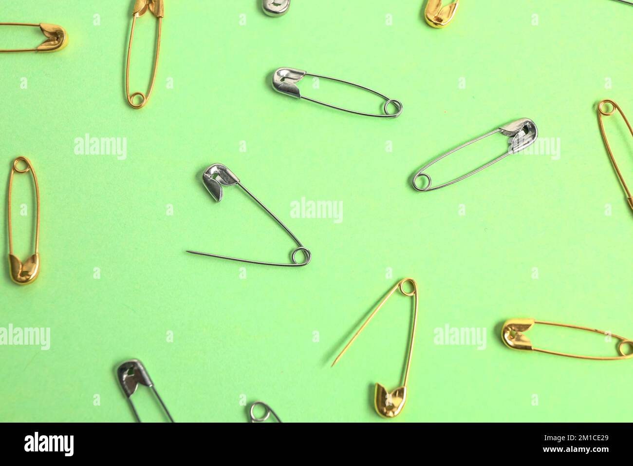 Different safety pins on green background Stock Photo - Alamy