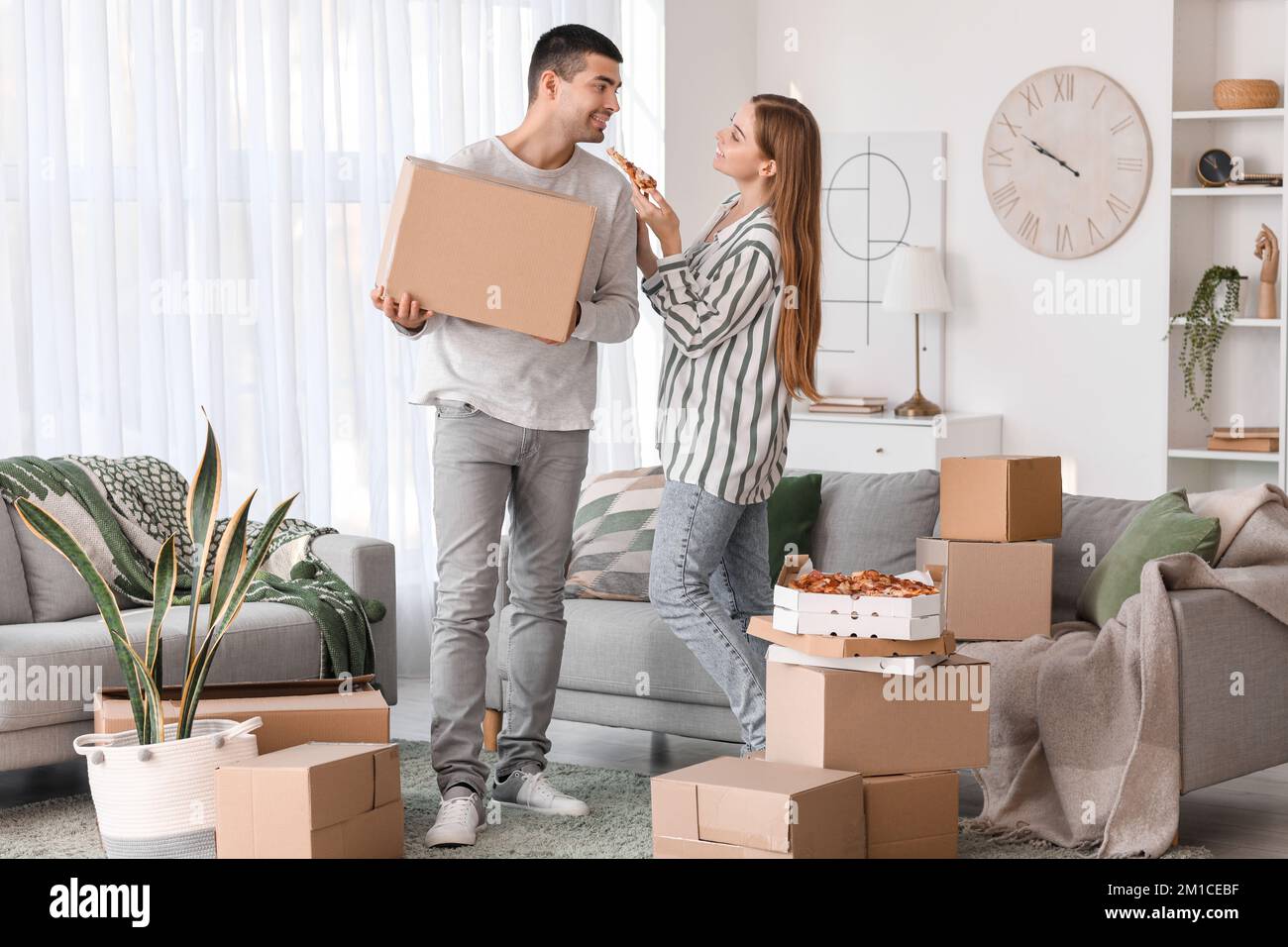 Happy young couple eating tasty pizza on moving day Stock Photo - Alamy
