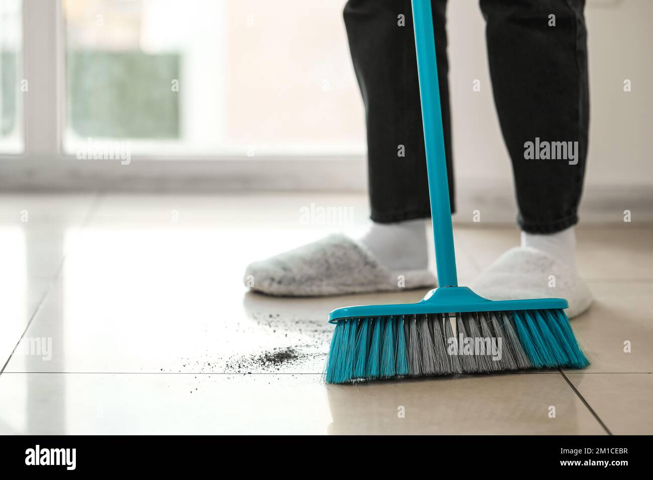 Woman sweeping tile floor with broom Stock Photo - Alamy