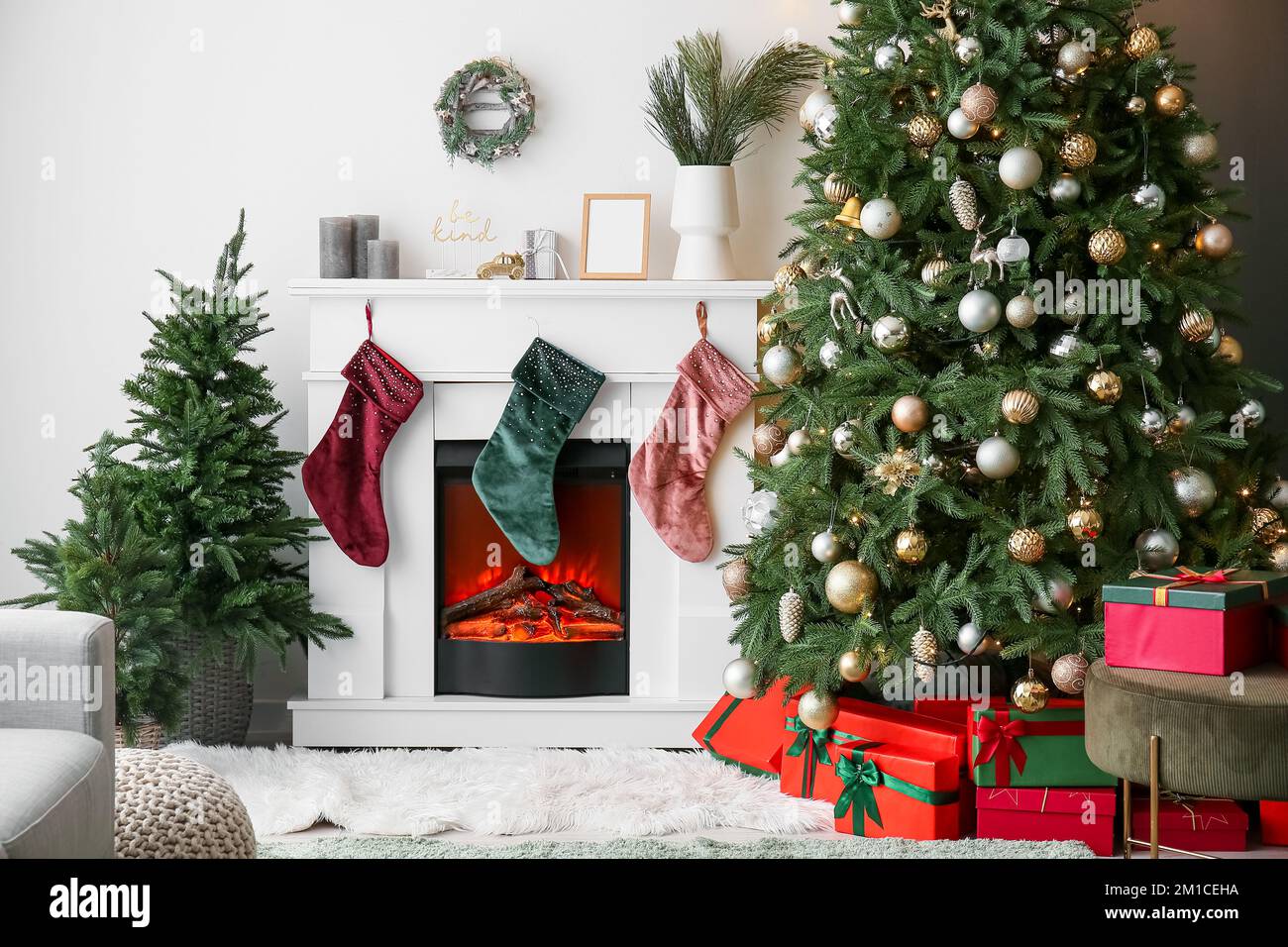 Interior of living room with electric fireplace and Christmas trees ...