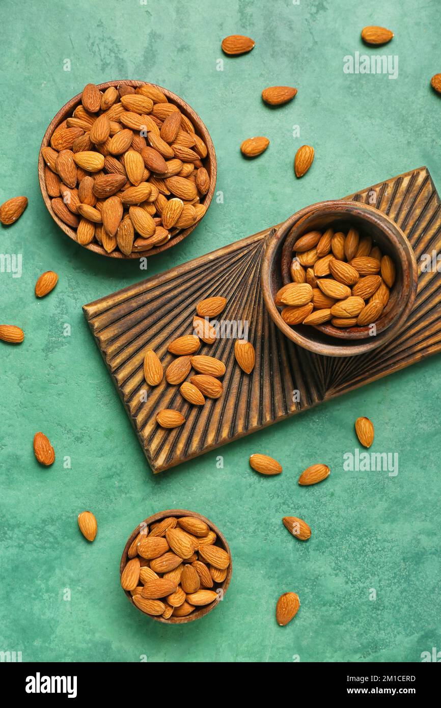 Board with bowls of almonds on green background Stock Photo - Alamy