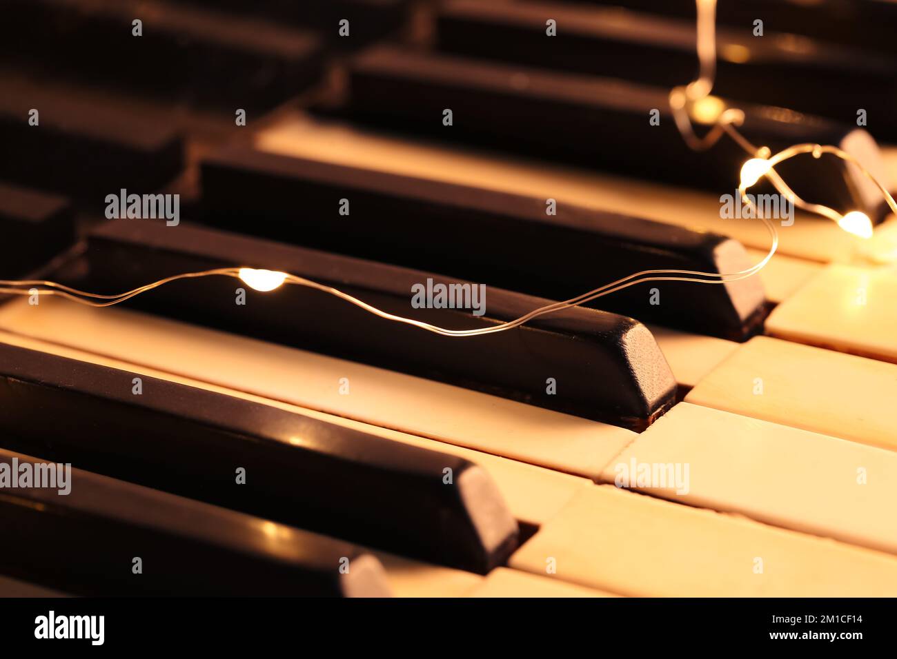 Piano keys with glowing Christmas lights, closeup Stock Photo - Alamy