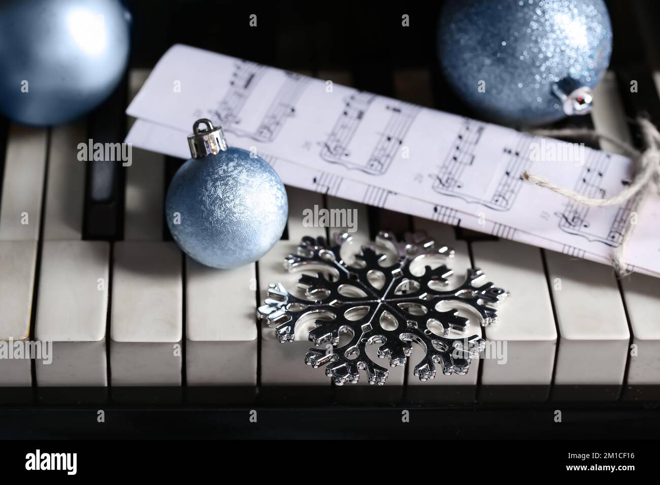 Christmas balls with note sheet and snowflake on piano keys, closeup ...