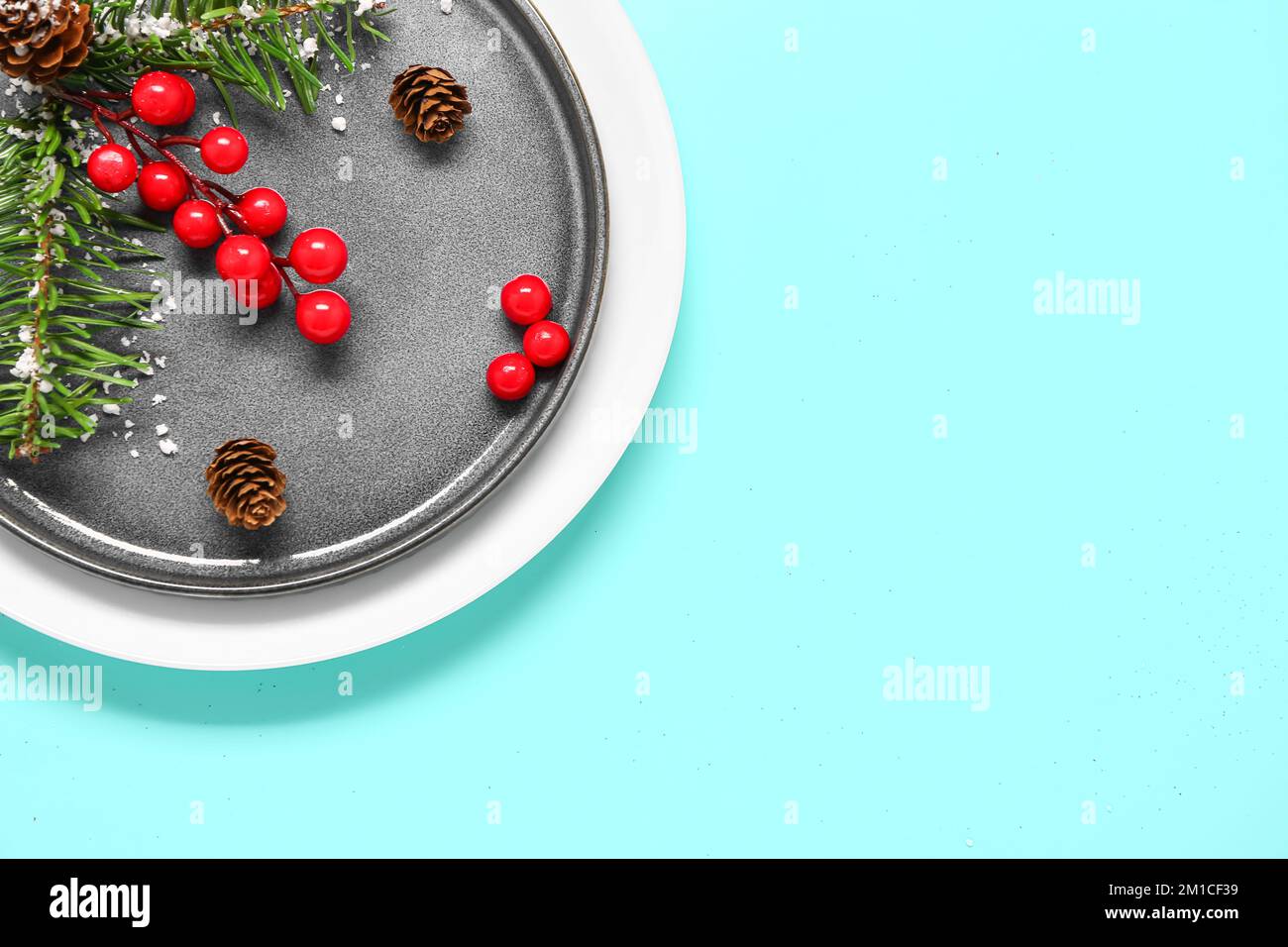 Plates with Christmas branches, fir cones and cranberry on blue ...