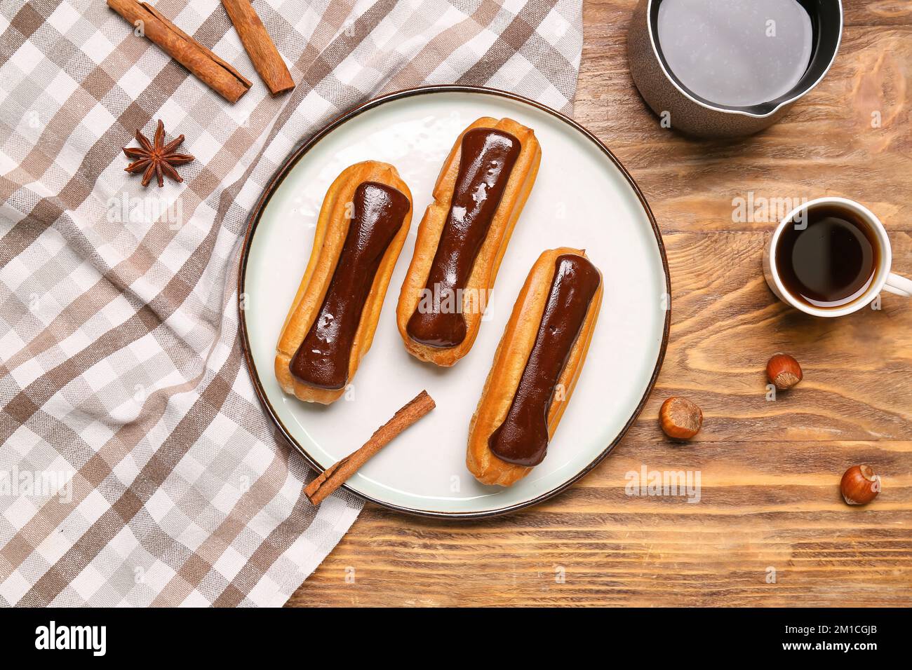 Plate with tasty chocolate eclairs and cup of coffee on wooden ...