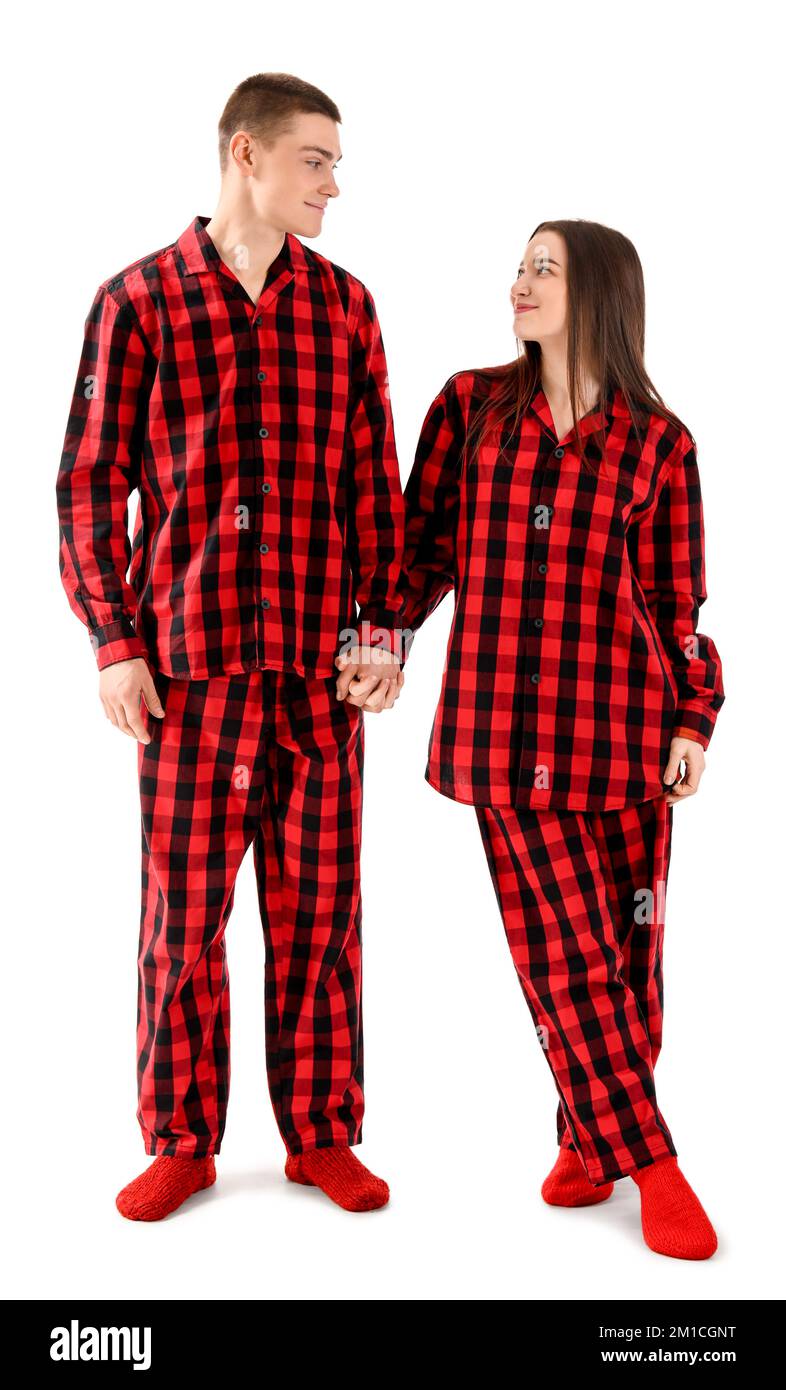 Young couple in checkered pajamas holding hands on white background ...