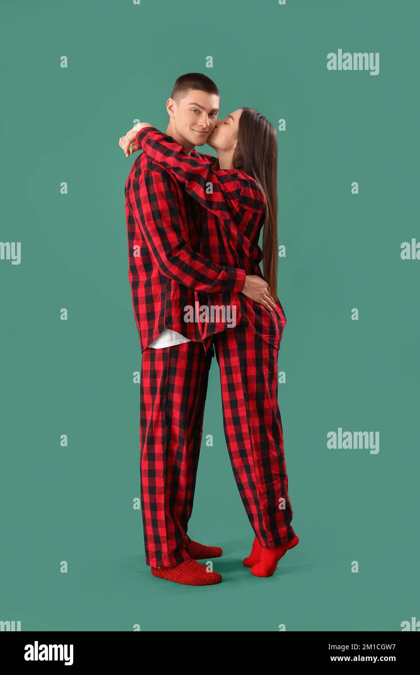 Young couple in checkered pajamas hugging on green background Stock ...