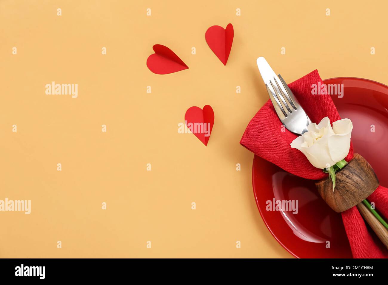 Table setting for Valentine's Day with paper hearts and rose on beige ...