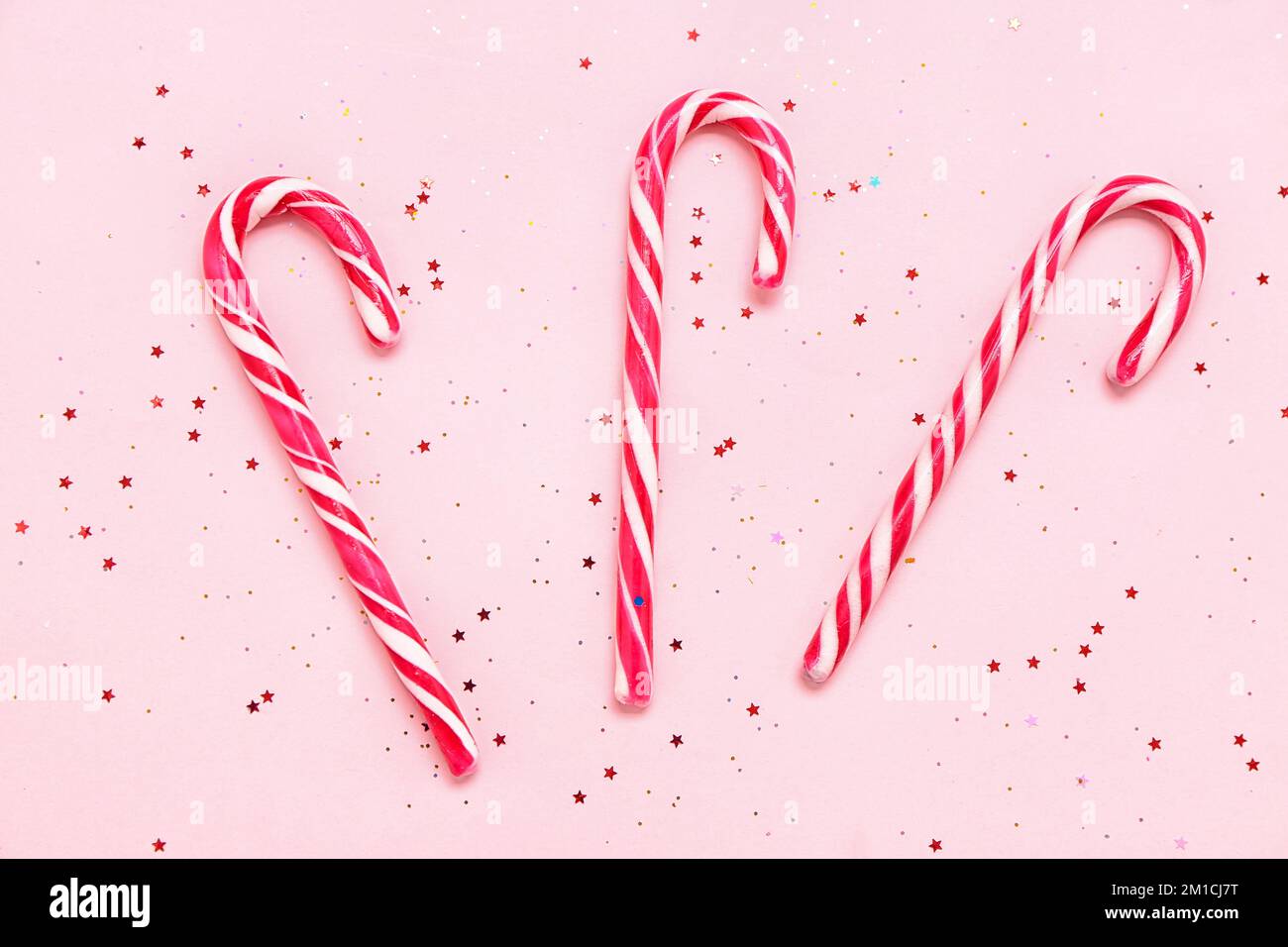 Composition with tasty candy canes and sequins on pink background Stock ...