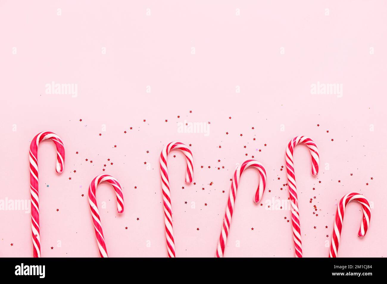 Composition with tasty candy canes and sequins on pink background Stock ...