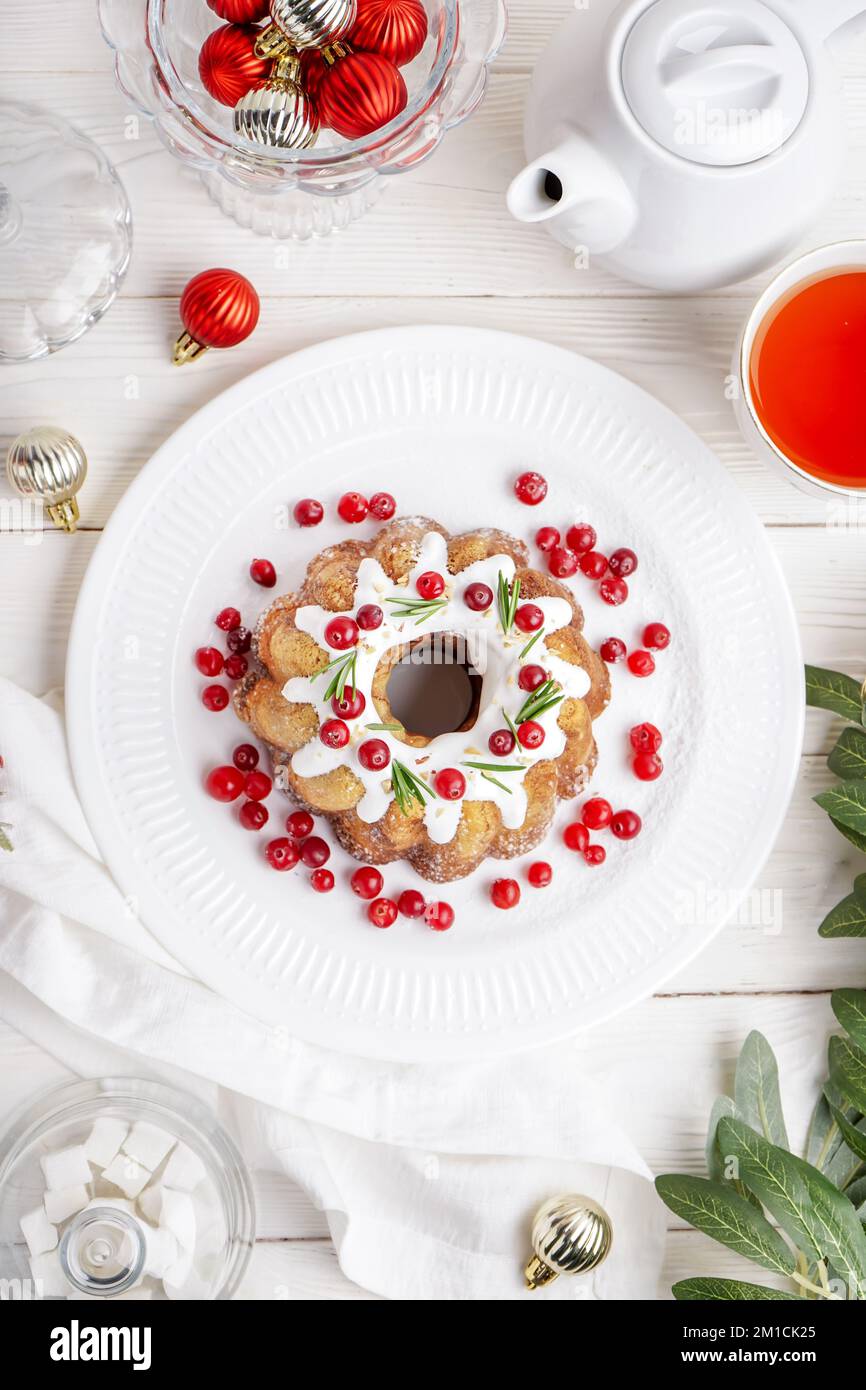 Plate of tasty Christmas cake, cup of tea and decorations on light ...