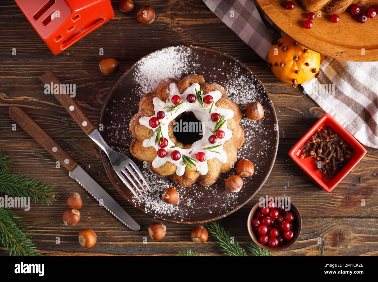 Plate with tasty Christmas cake, hazelnuts, cranberry and cloves on ...