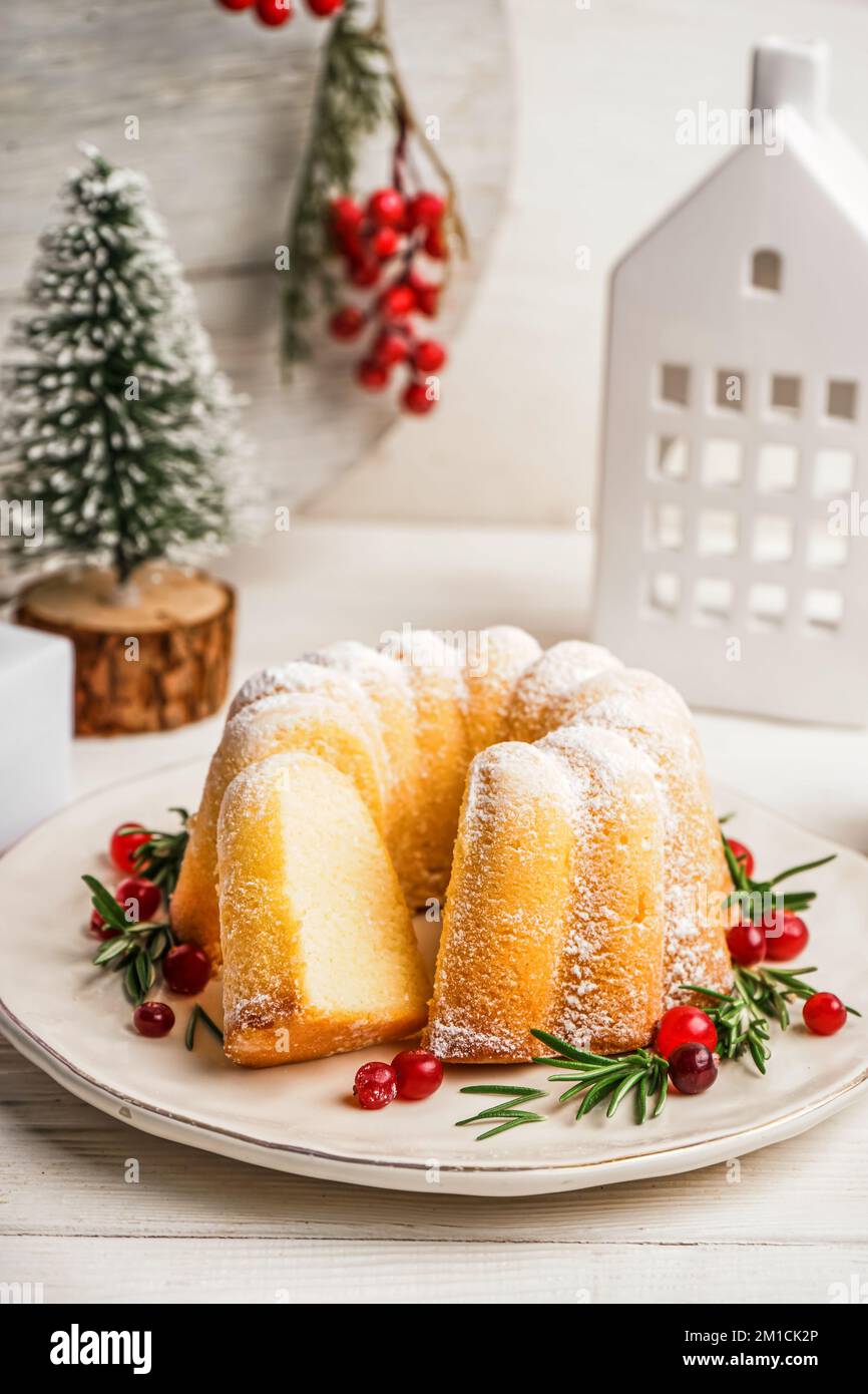 Plate with tasty Christmas cake and decorations on light wooden table ...