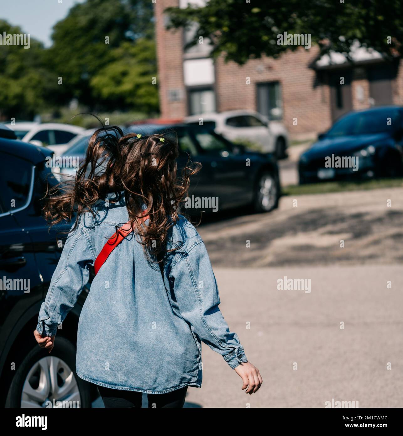 A back shot of a caucasian casual girl wearing jean jacket and short ...