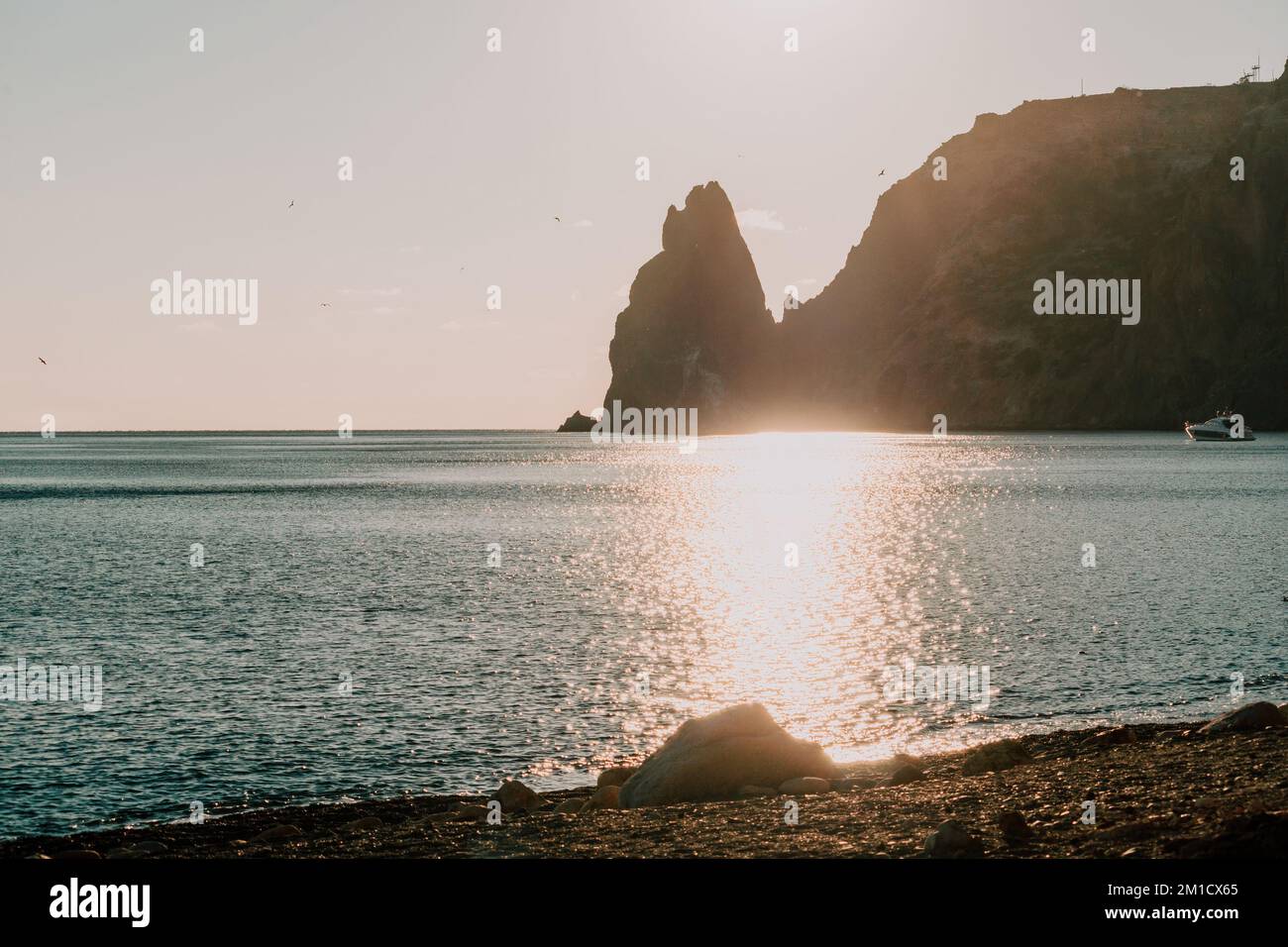 A red burning sunset over the sea with rocky volcanic cliff. Abstract ...