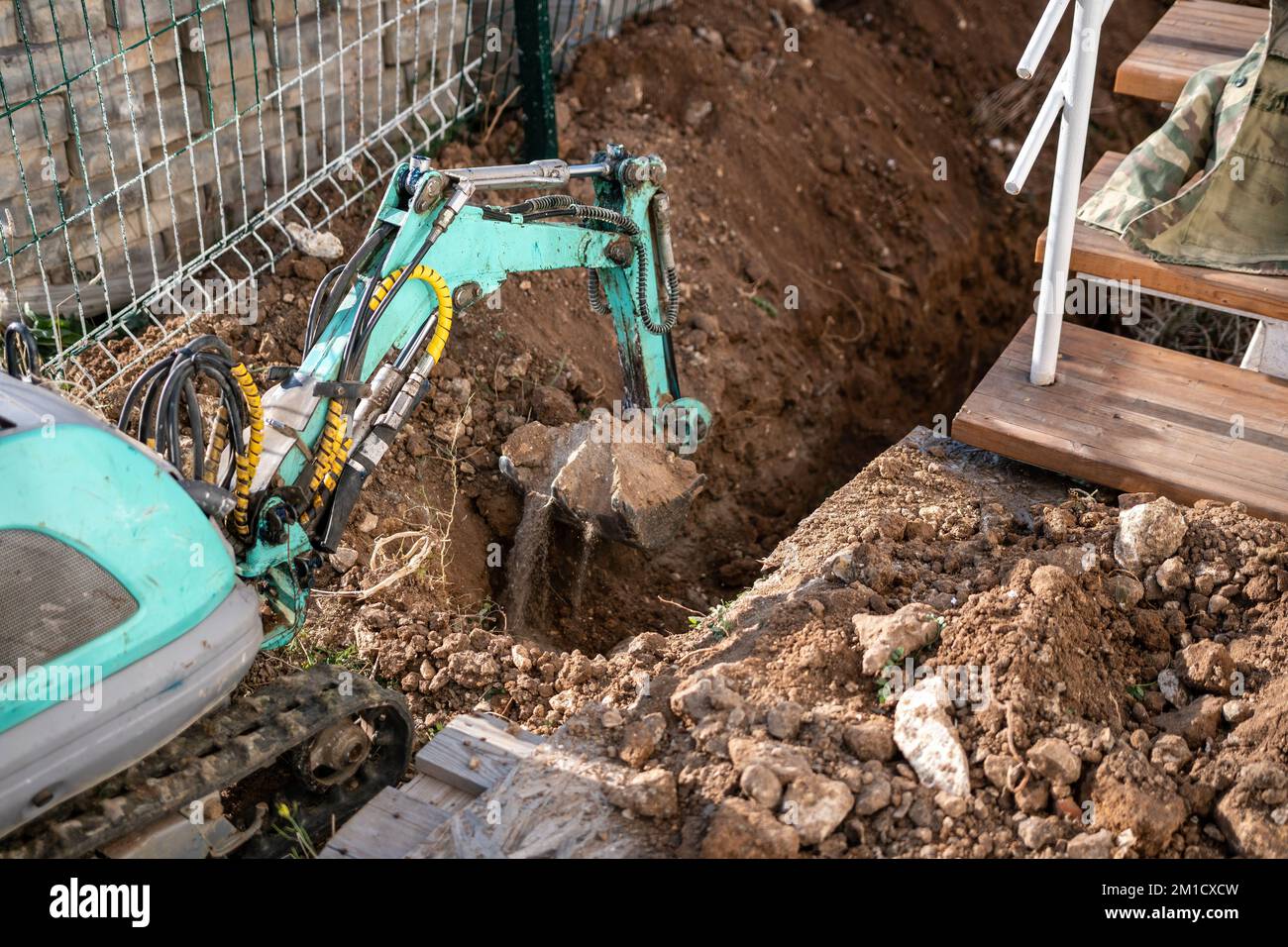 Mini excavator digs a trench to lay pipes. Close up of an excavator ...