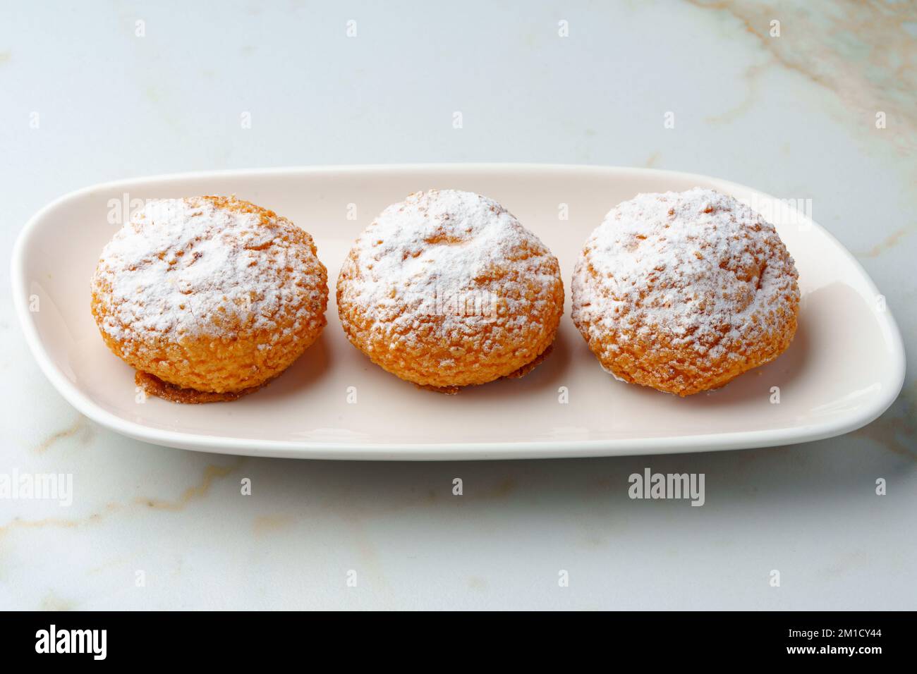 Homemade profiteroles with powdered sugar on white plate Stock Photo ...