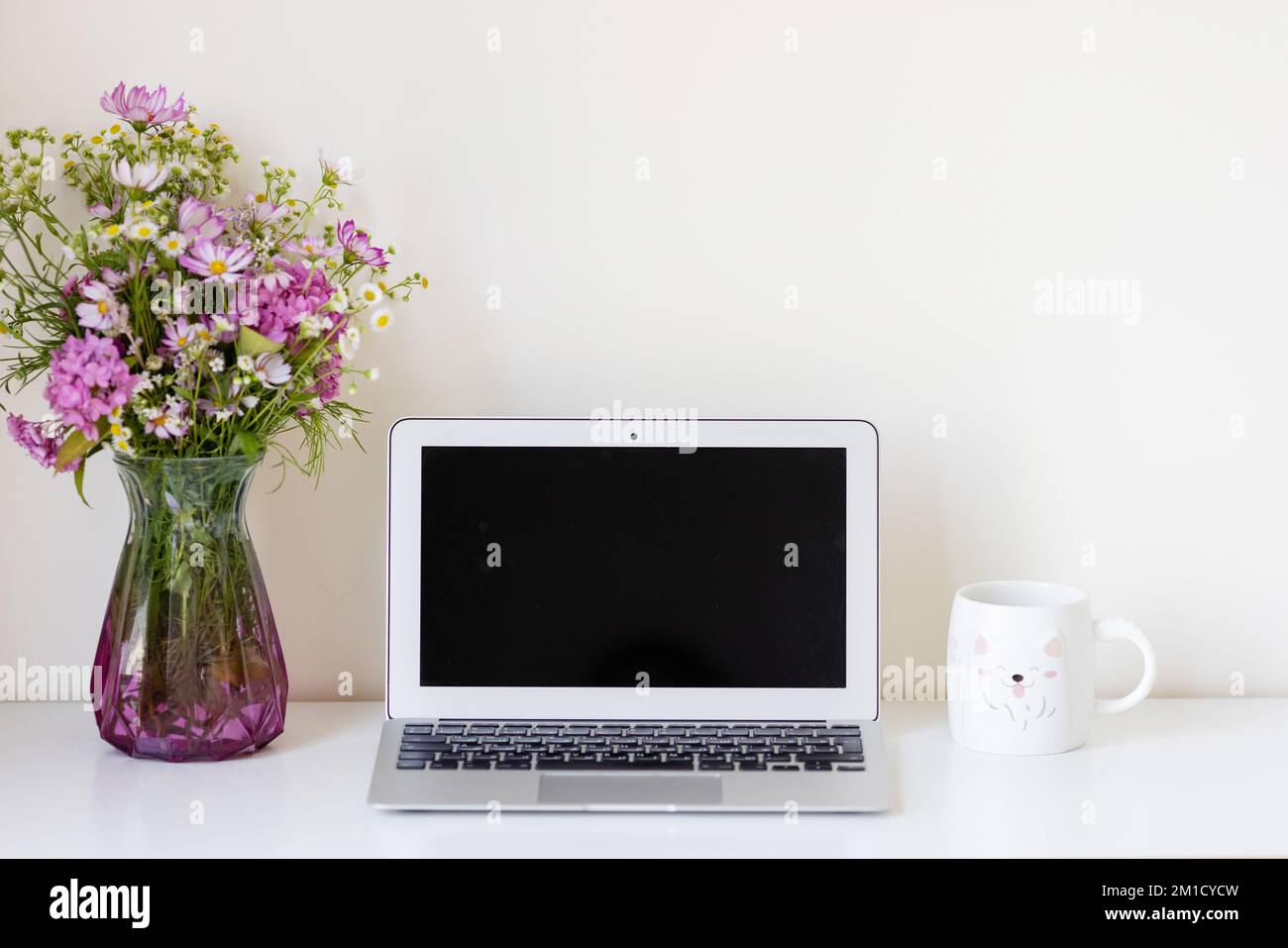 Modern workplace with laptop computer, coffee cup and bouquet of ...