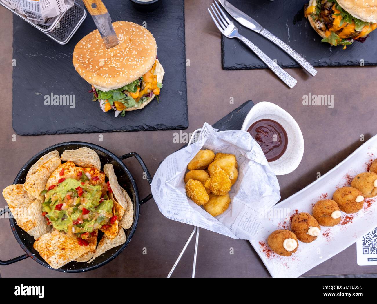 A top view of nachos and burgers served with French fries and ...