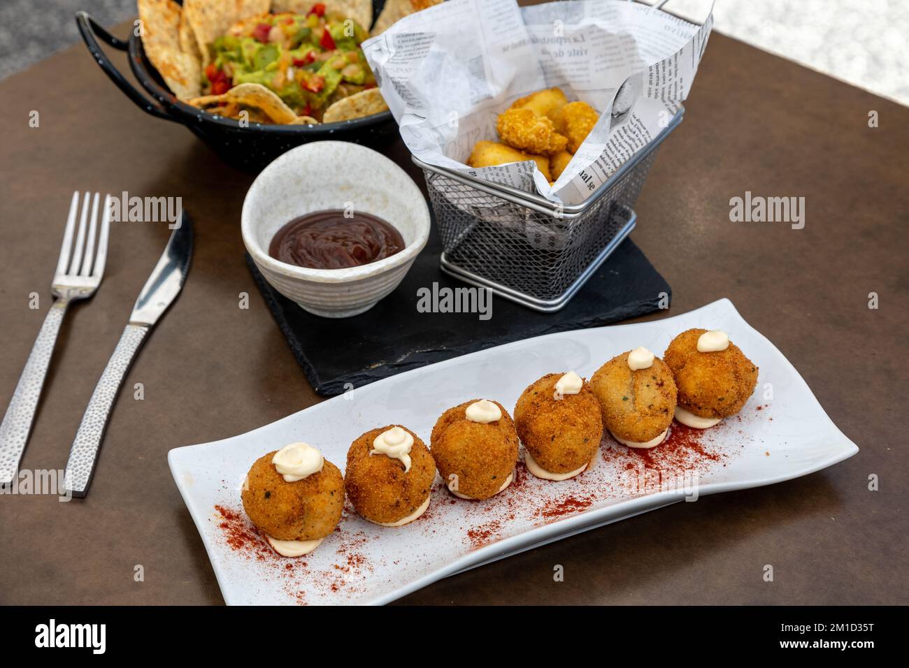A closeup of fried mozzarella balls served with ketchup and nachos in a ...